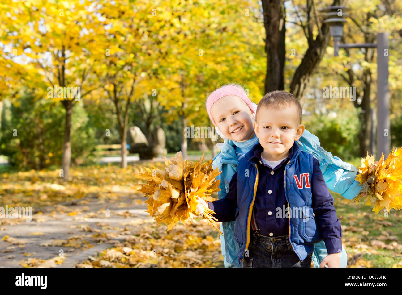 Happy smiling little brother and sister playing with autumn leaves in a ...