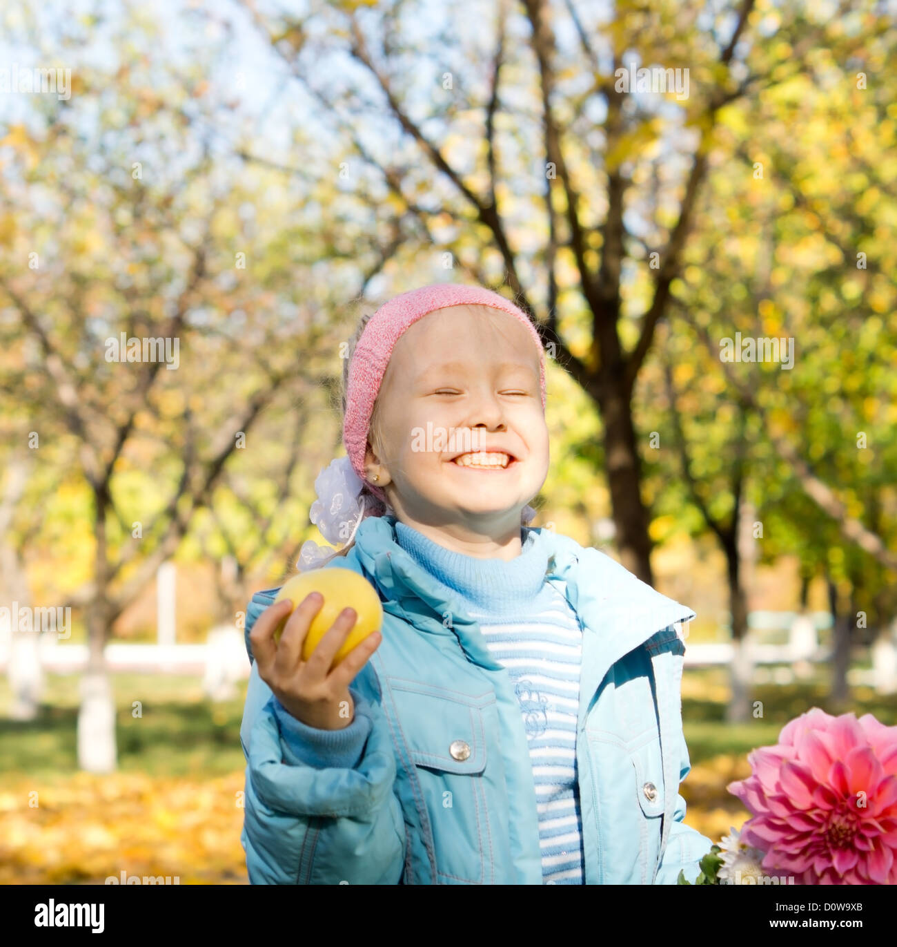 Little girl with a cheesy mischievous grin holding an apple and a fresh ...
