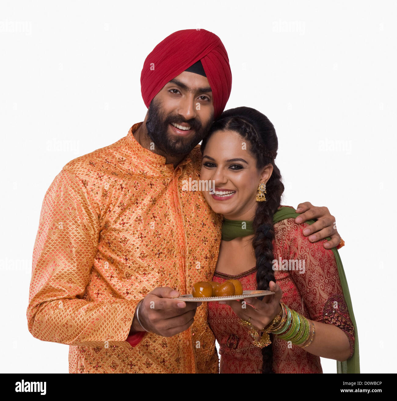 Sikh couple holding a plate of gulab jamuns the traditional Indian ...
