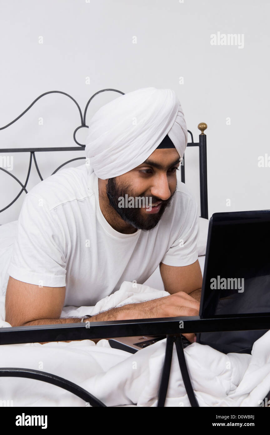 Sikh man working on a laptop on the bed Stock Photo - Alamy