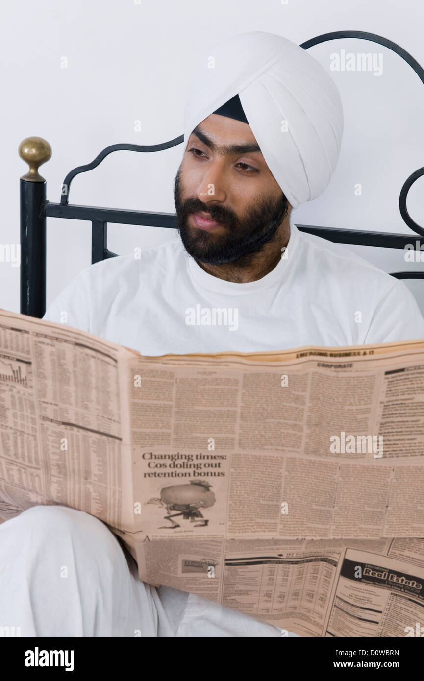 Sikh man reading a newspaper on the bed Stock Photo - Alamy