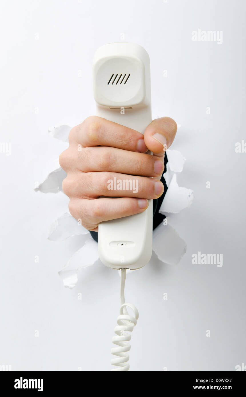 Hand holding phone through hole in paper Stock Photo - Alamy