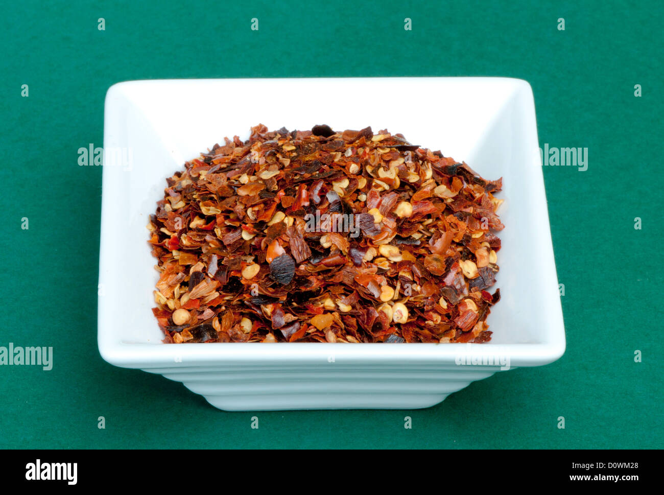 Coarsely ground red pepper and whole dried peppers.Green background ...