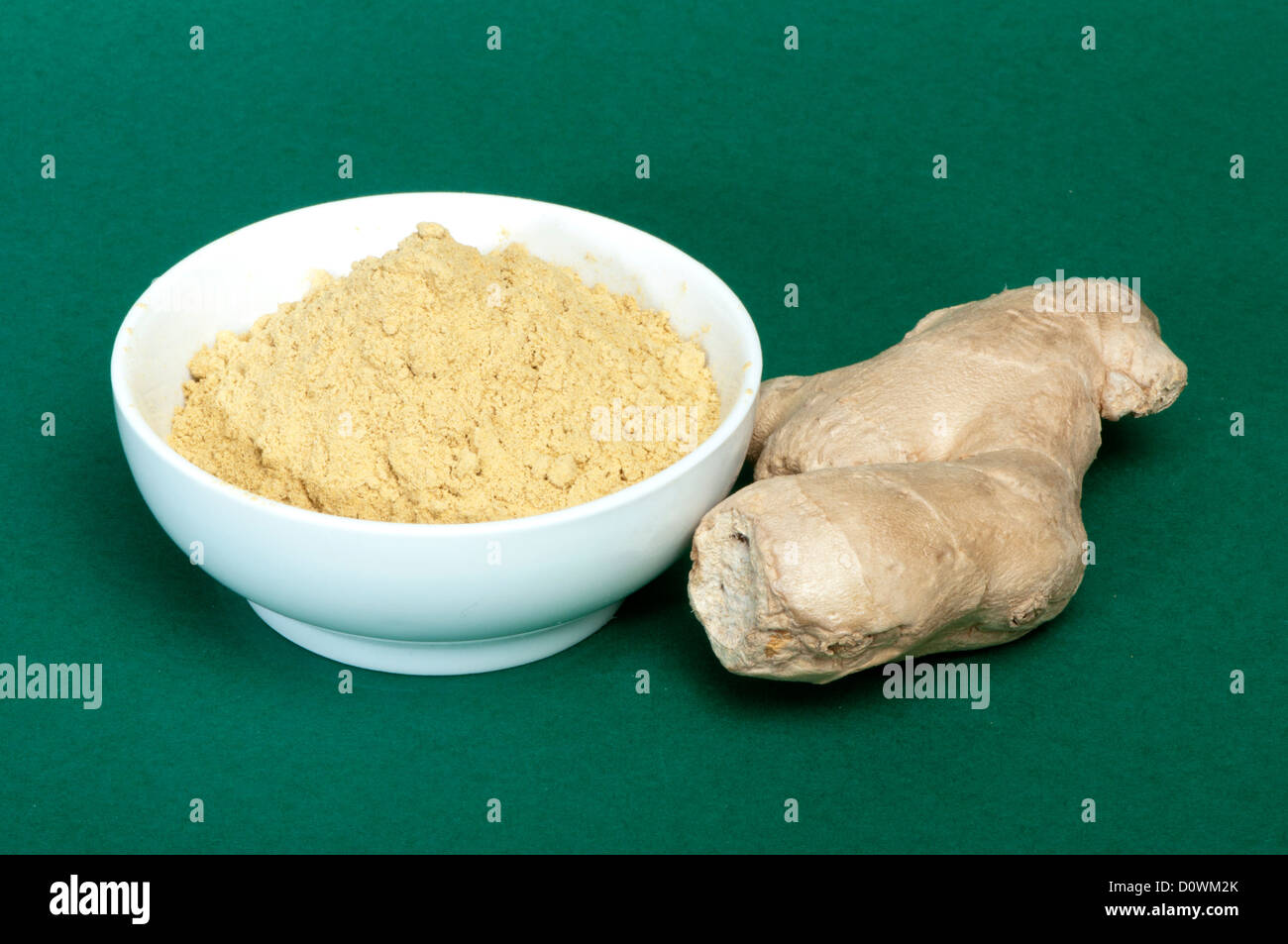 Powdered ginger in a bowl and whole ginger on green background Stock ...