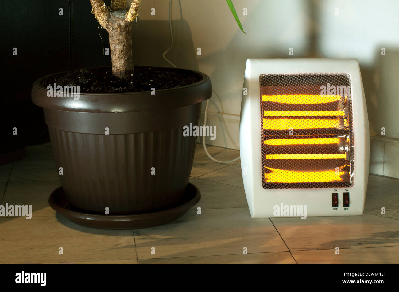 Electric heater with halogen coils. Flower pot and heater on marble ...