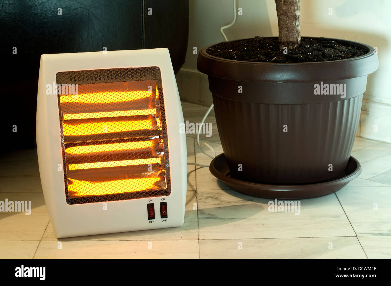 Electric heater with halogen coils. Flower pot and heater on marble ...