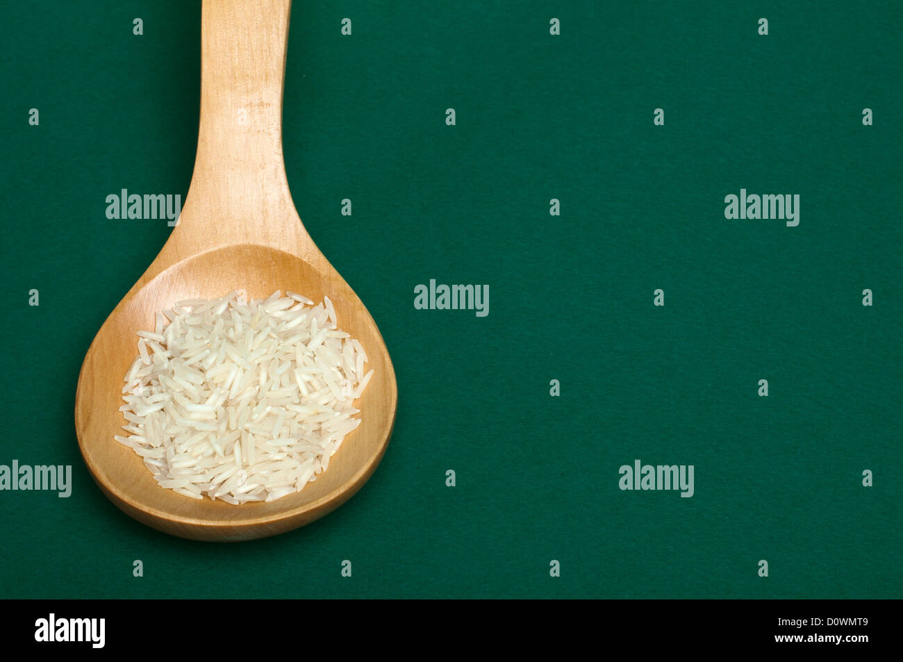 Basmati rice in wooden spoon on green background Stock Photo - Alamy
