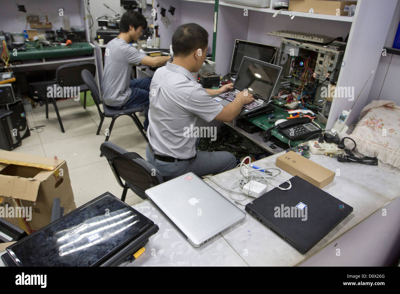 Two electronics engineers repairing laptop computers at a retail unit ...