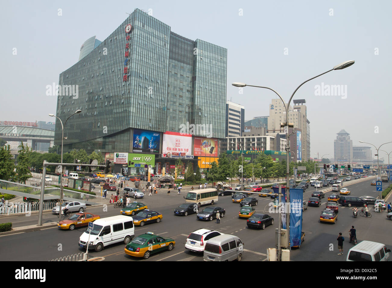 A busy intersection with cars and taxis driving past the Zhongguancun e ...