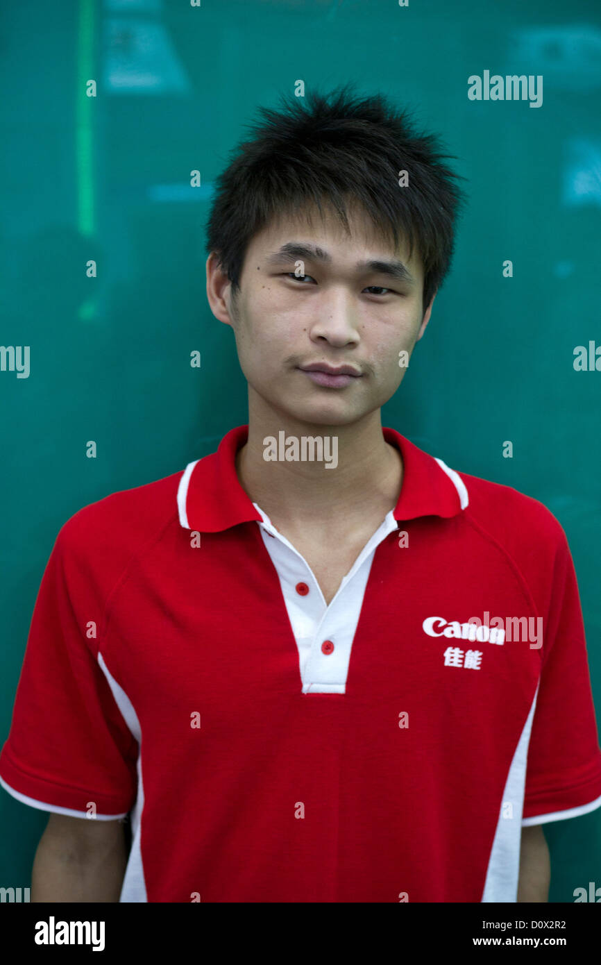 A young Chinese male wearing a red polo shirt with a Canon logo ...