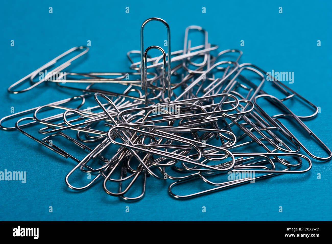 A pile of paper clips, on a blue background Stock Photo - Alamy
