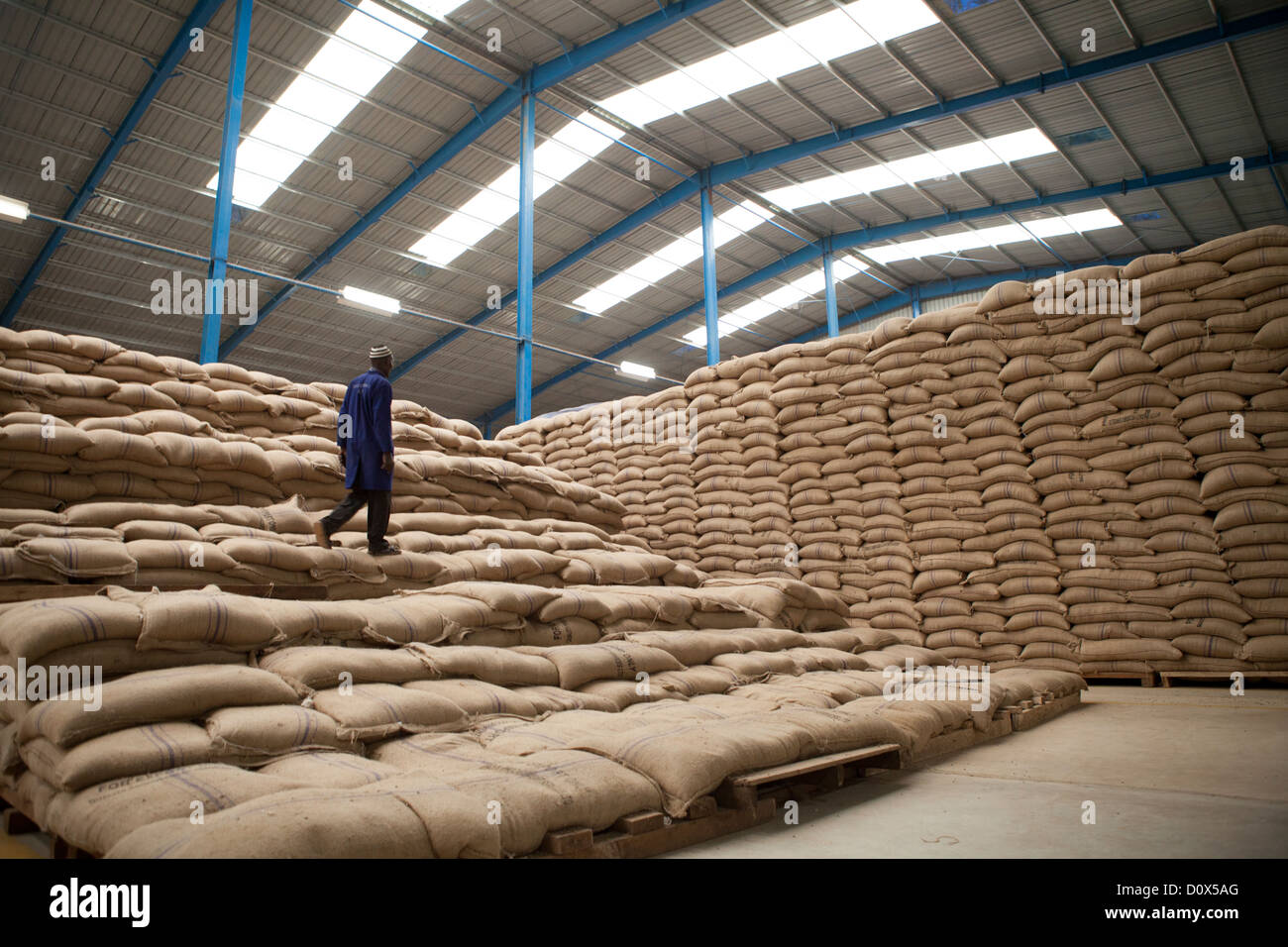 A worker walks through stacks of coffee and commodities at a warehouse in Kampala, Uganda, East ...