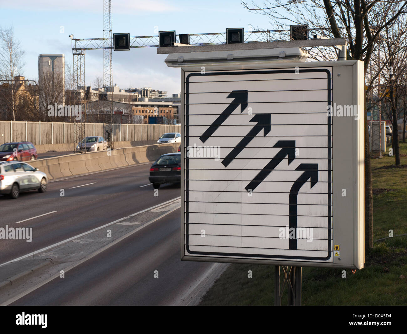 Variable traffic sign with four black arrows on white pointing ...