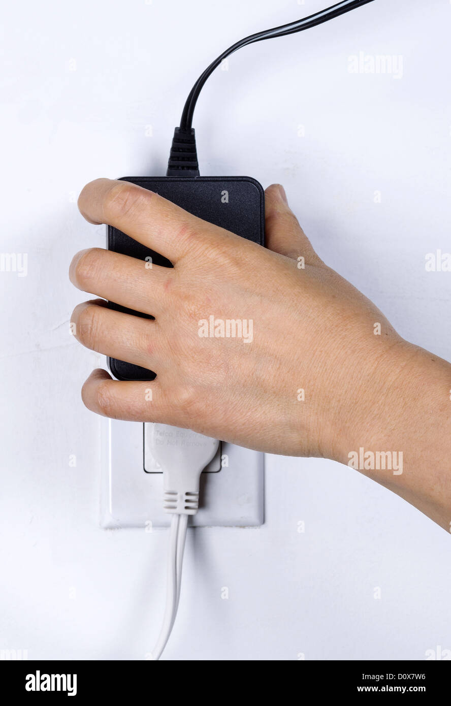 Female hand plugging in power supply into electrical outlet in garage ...