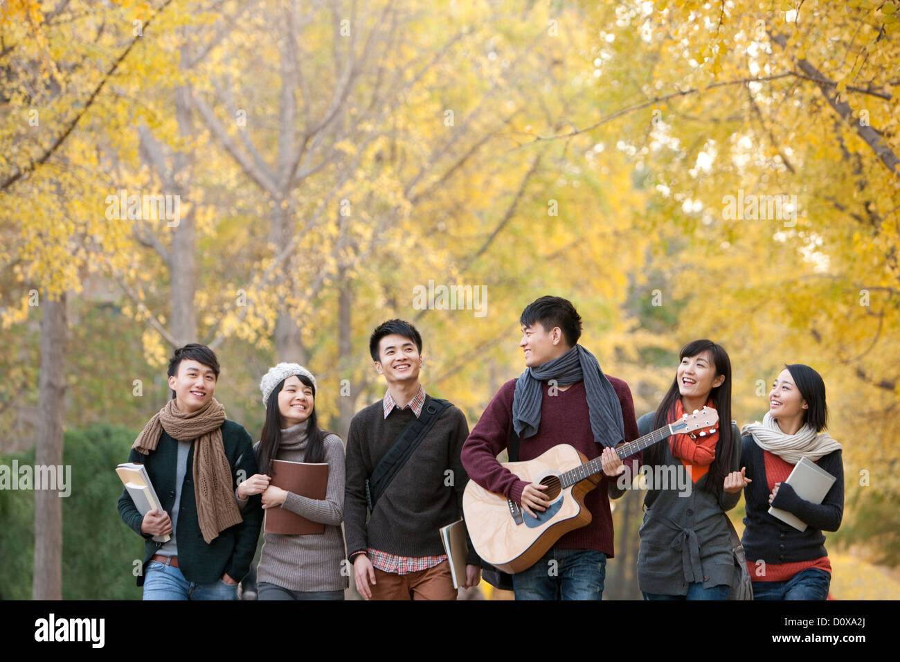College students walking and playing guitar on campus in autumn Stock ...