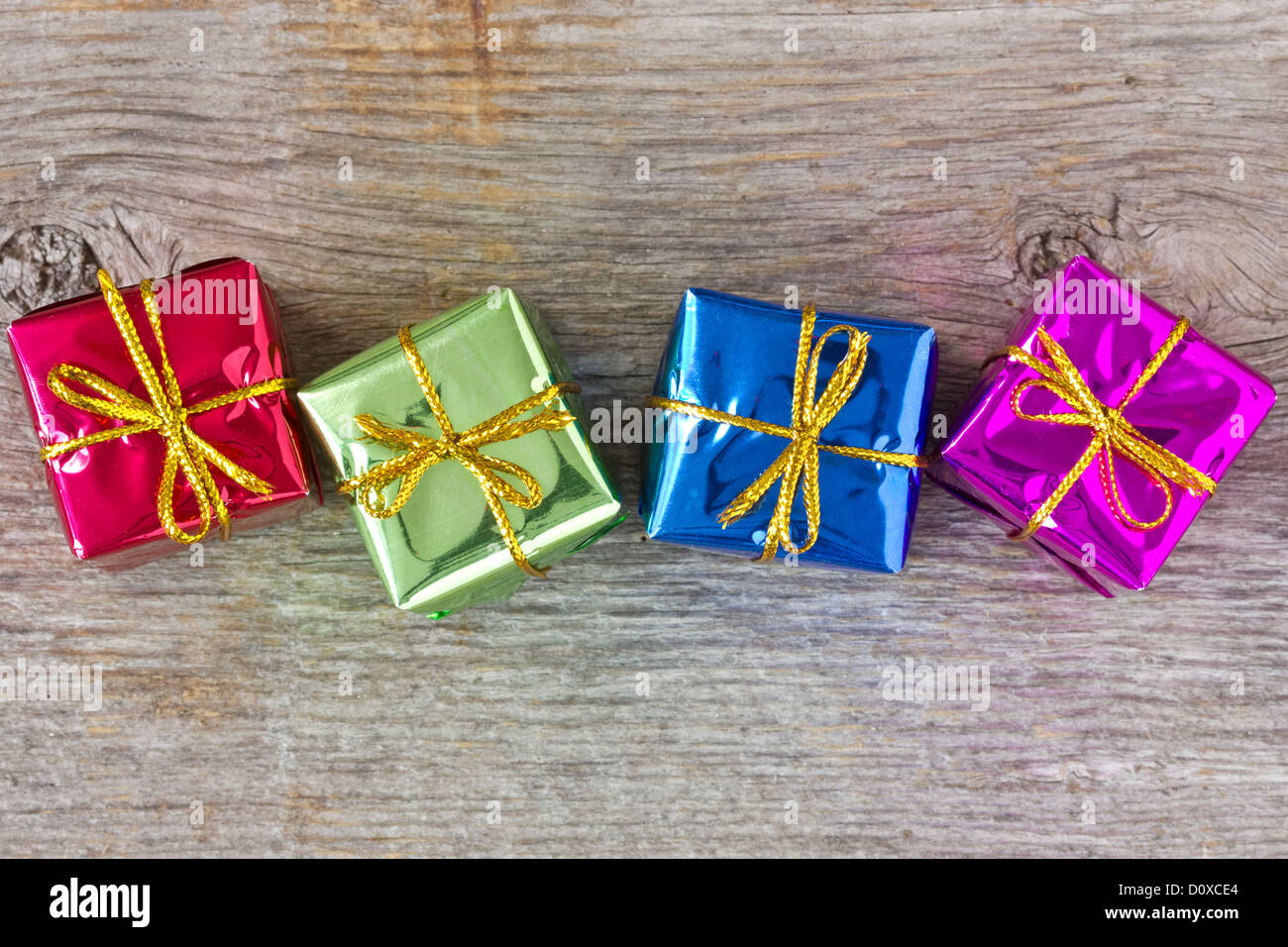 Four colorful gift boxes on the wooden floor Stock Photo - Alamy