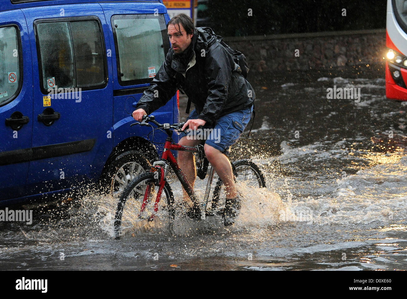 A cyclist rides his bike through flood water on a road in Bristol ...