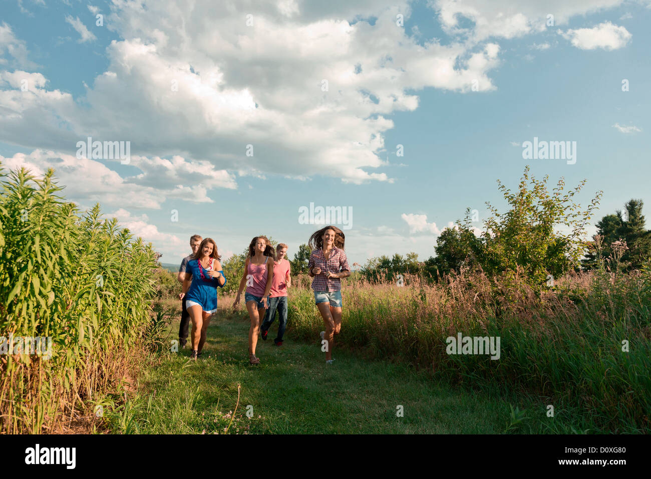 Five friends running through field Stock Photo - Alamy