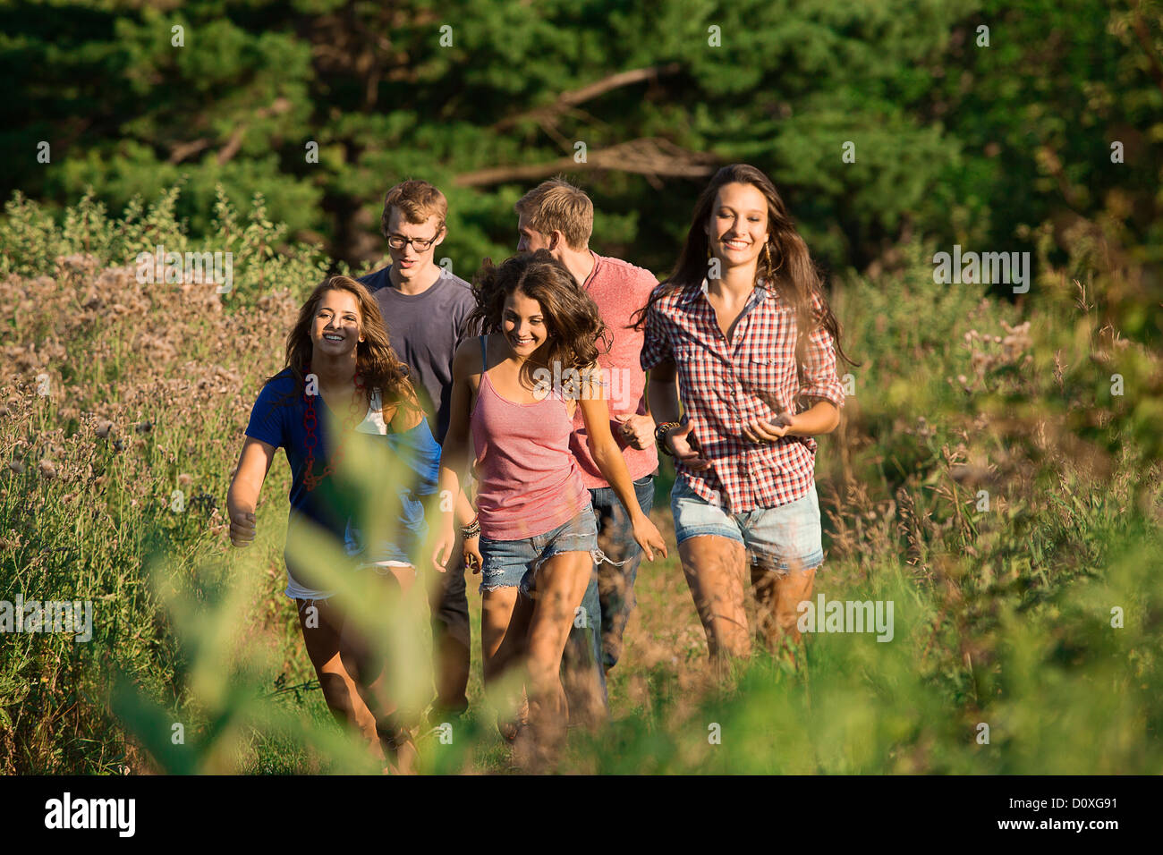 Five friends walking through field Stock Photo - Alamy