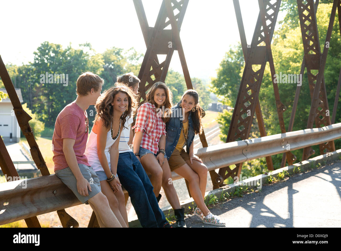 Group of friends sitting on bridge Stock Photo - Alamy