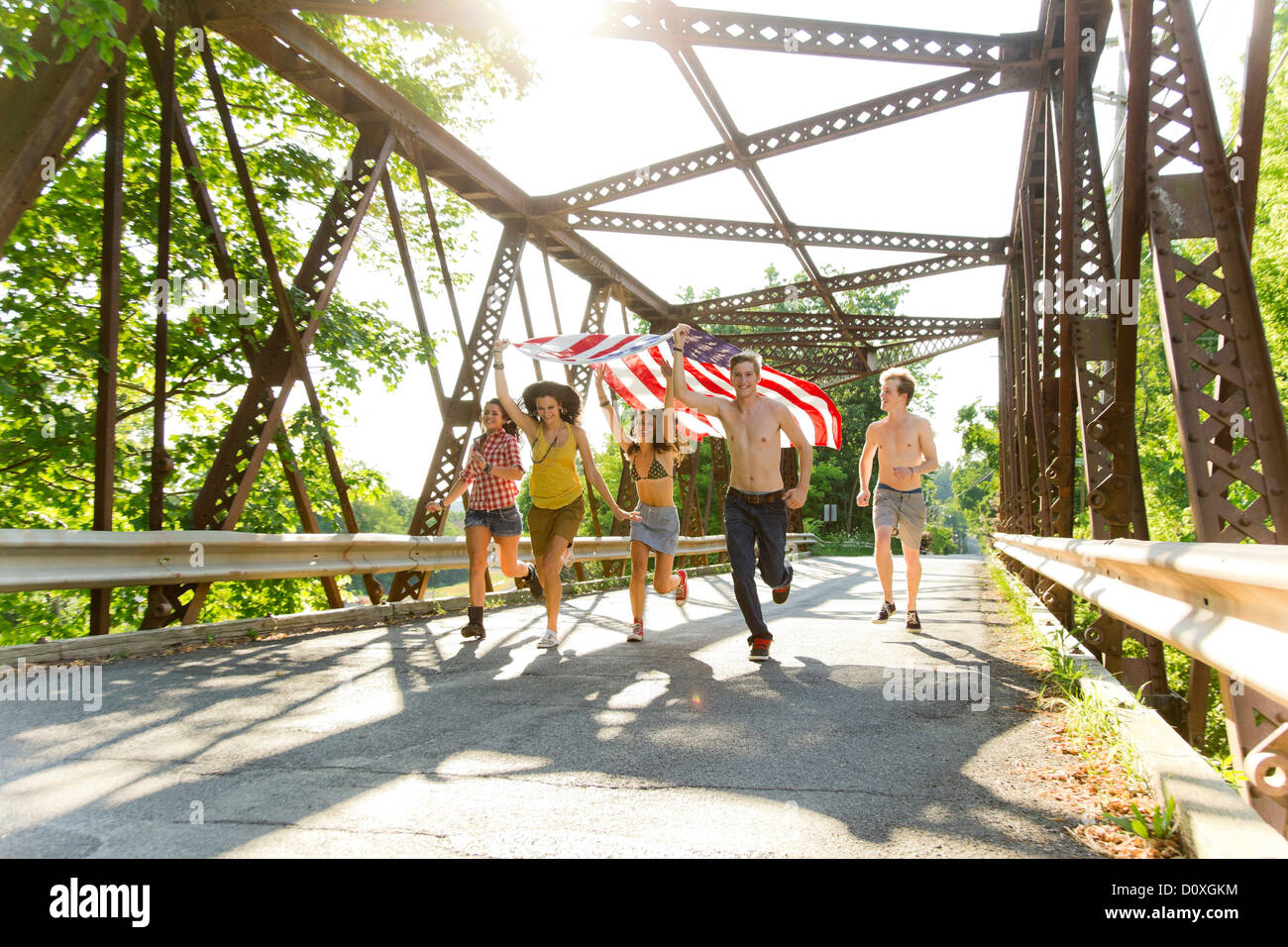 Group of friends running on bridge holding american flag Stock Photo ...