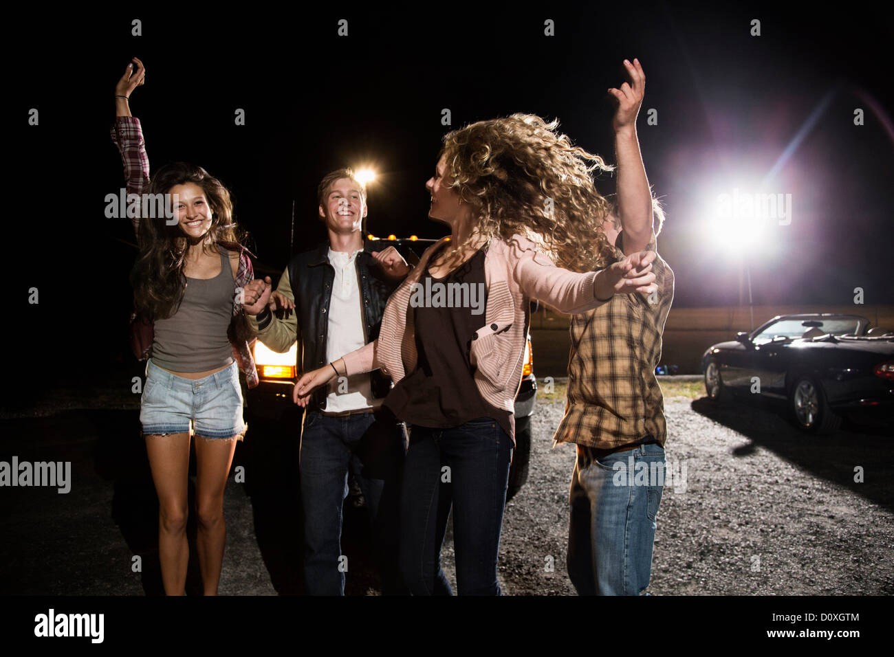 Four friends in parking lot at night Stock Photo - Alamy