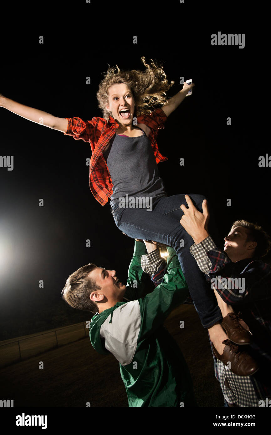 Two male friends lifting teenage girl, arms outstretched Stock Photo ...