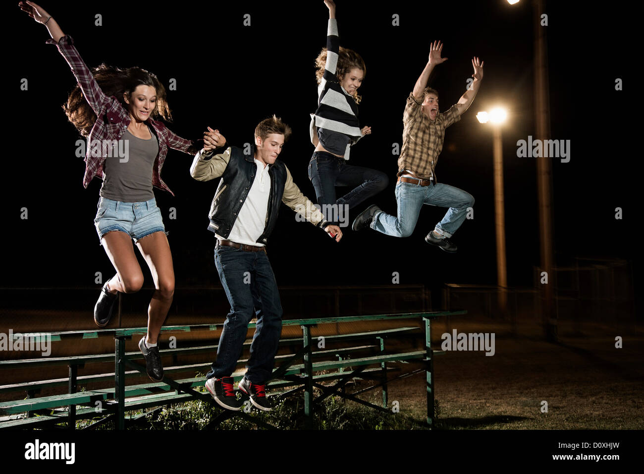 Four friends jumping over bleachers at night Stock Photo - Alamy