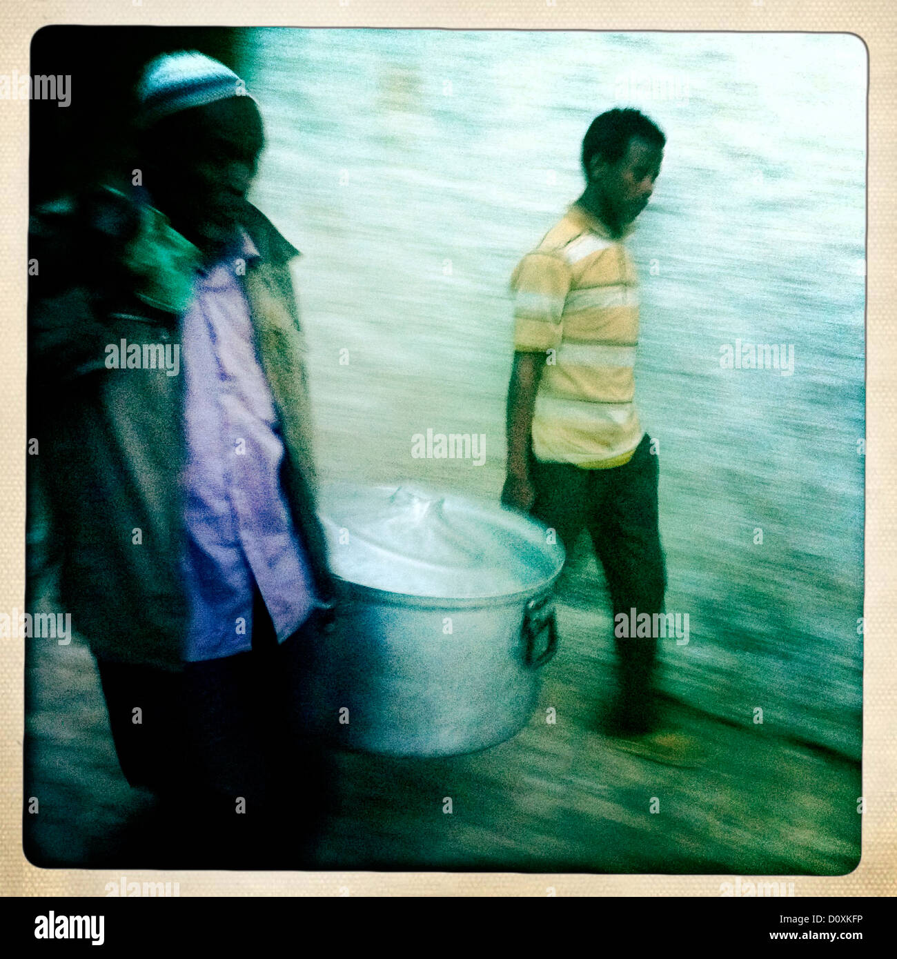 Two Men Carrying A Huge Cooking Pot For Charity Meal In A Street Of ...
