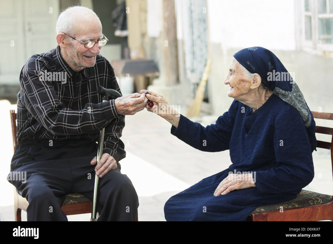 Senior man giving cherry to woman Stock Photo - Alamy