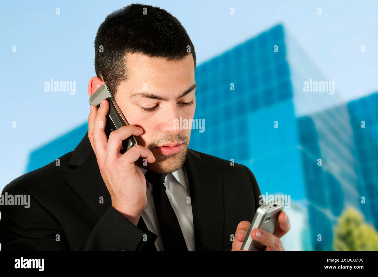 Young executive using two mobile phones Stock Photo - Alamy