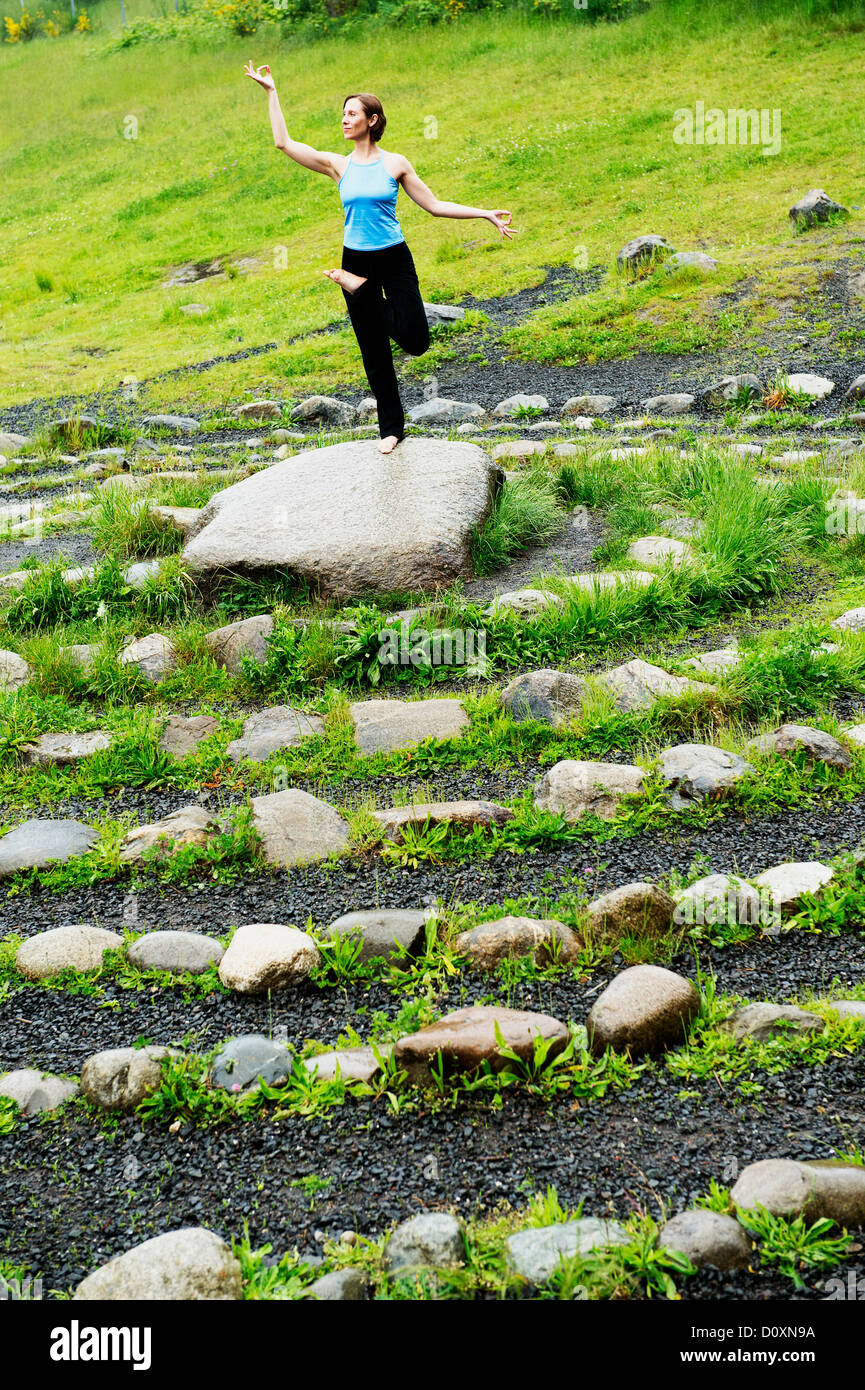 Woman in yoga pose on stone in maze Stock Photo - Alamy