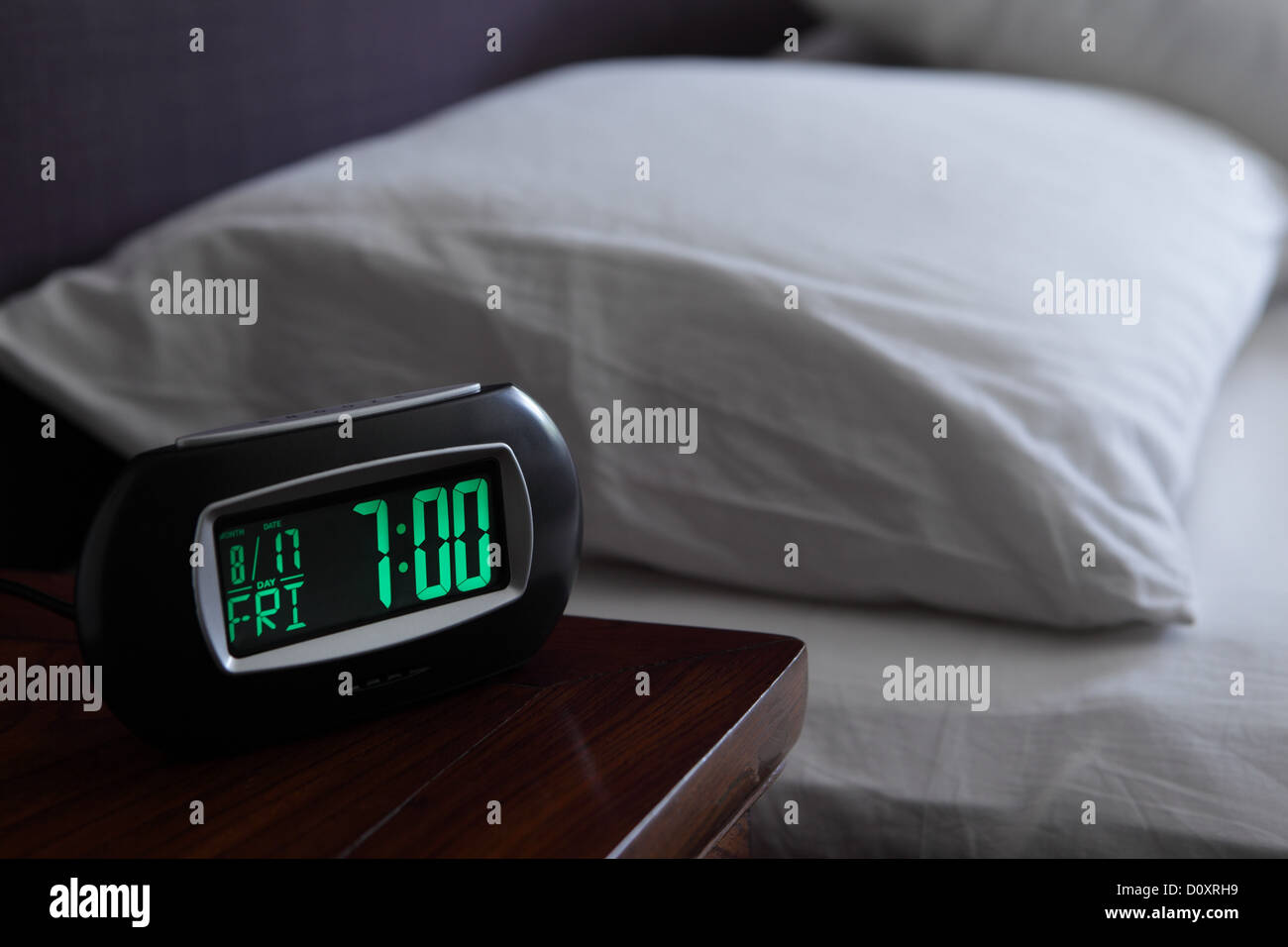Alarm clock by bed Stock Photo - Alamy