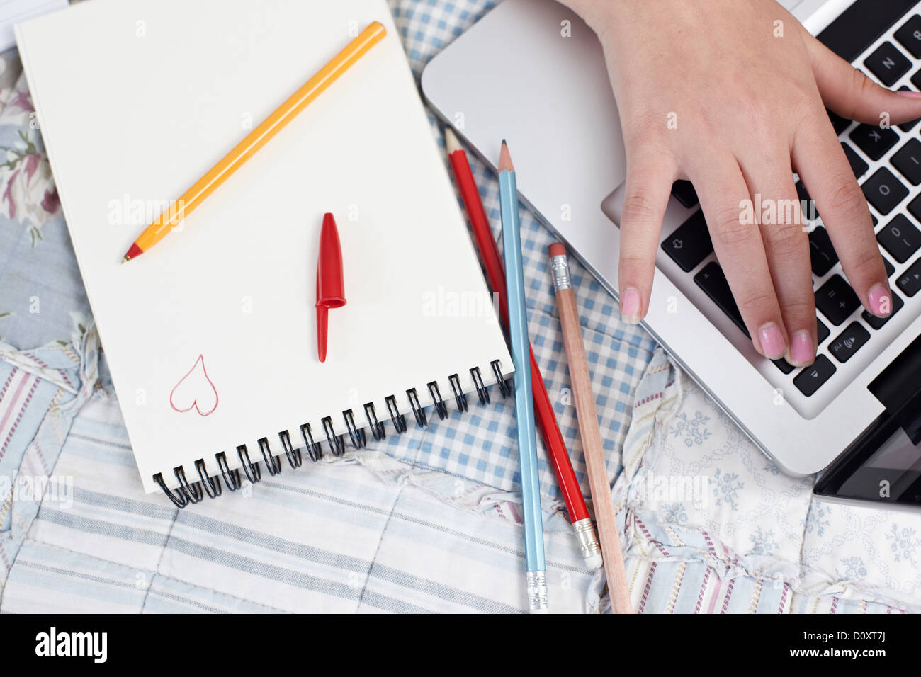Teenage girl using laptop with notepad and pencils Stock Photo - Alamy