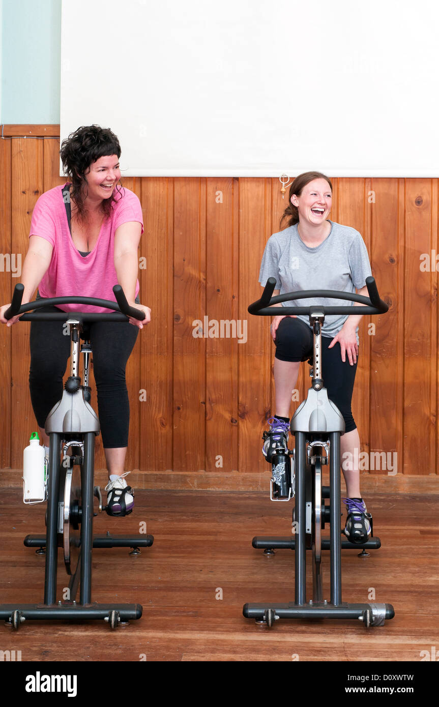 Two women on exercise bikes Stock Photo - Alamy