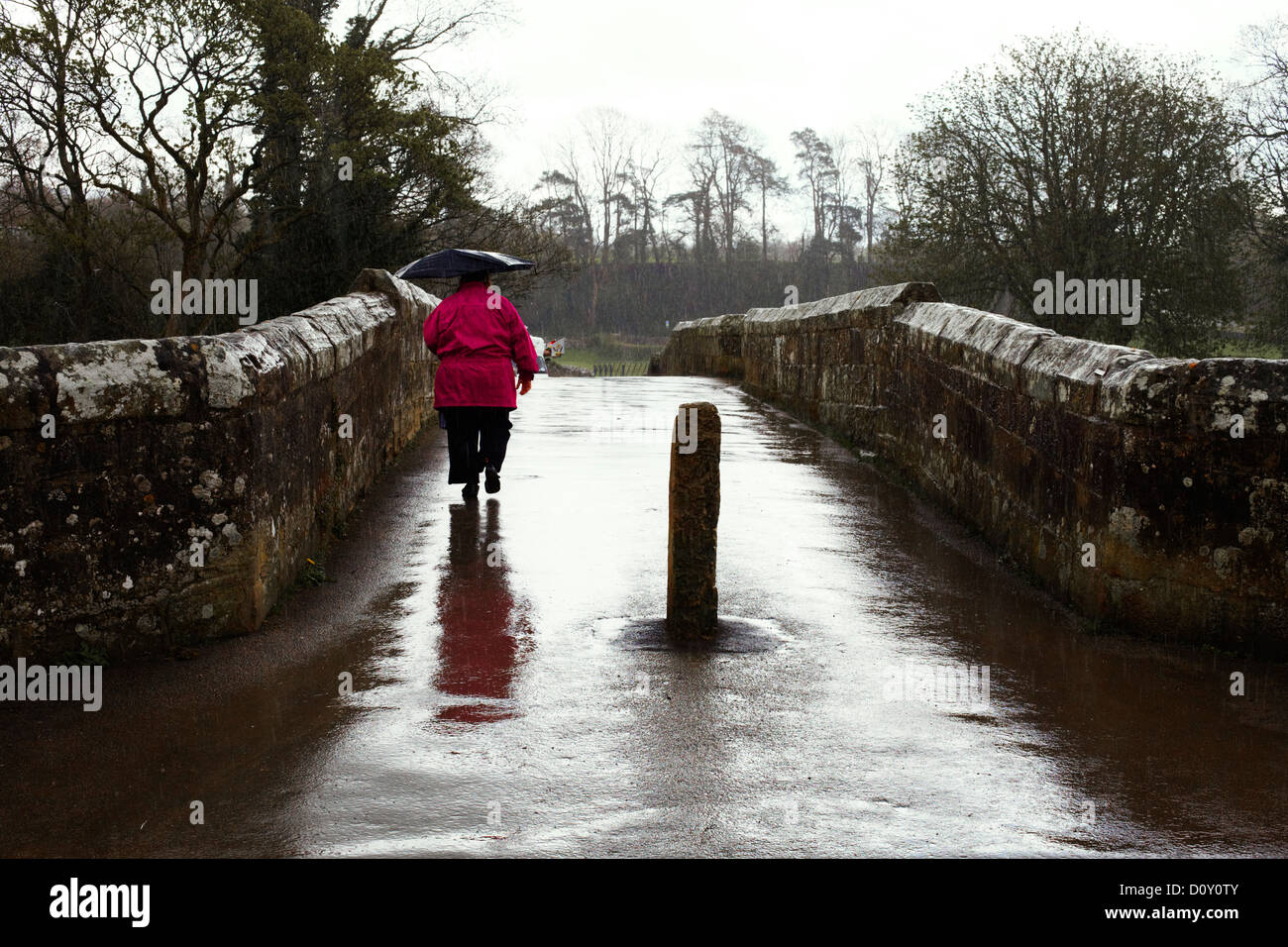 Woman in red coat walking in rain over a bridge Stock Photo - Alamy
