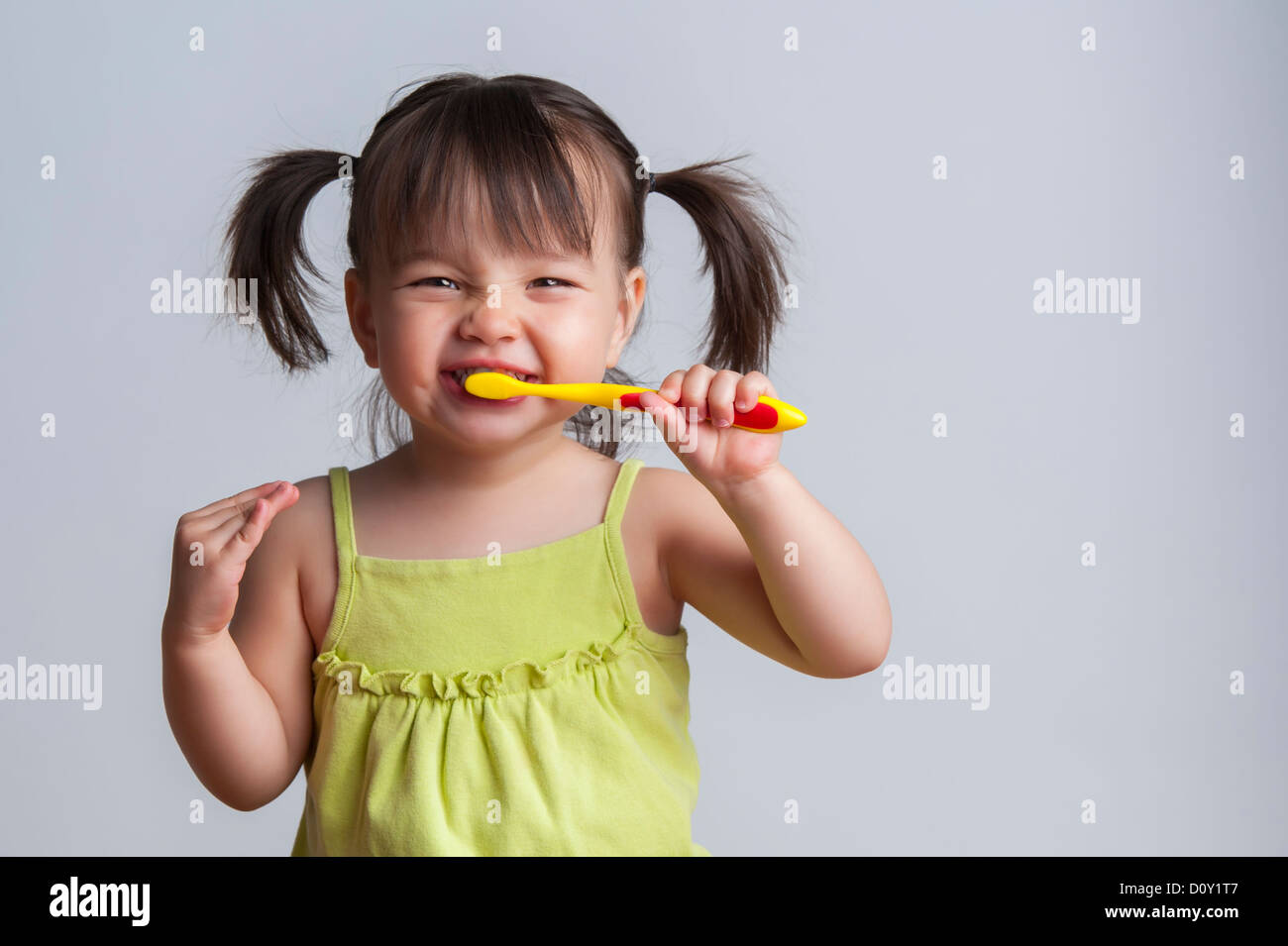 Toddler smiling while brushing her teeth Stock Photo - Alamy