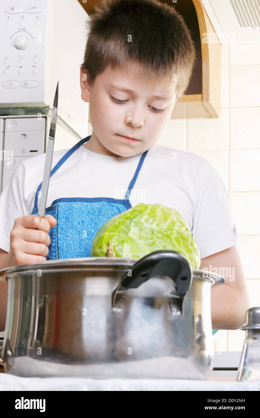 Kid at kitchen with cabbage and knife Stock Photo - Alamy