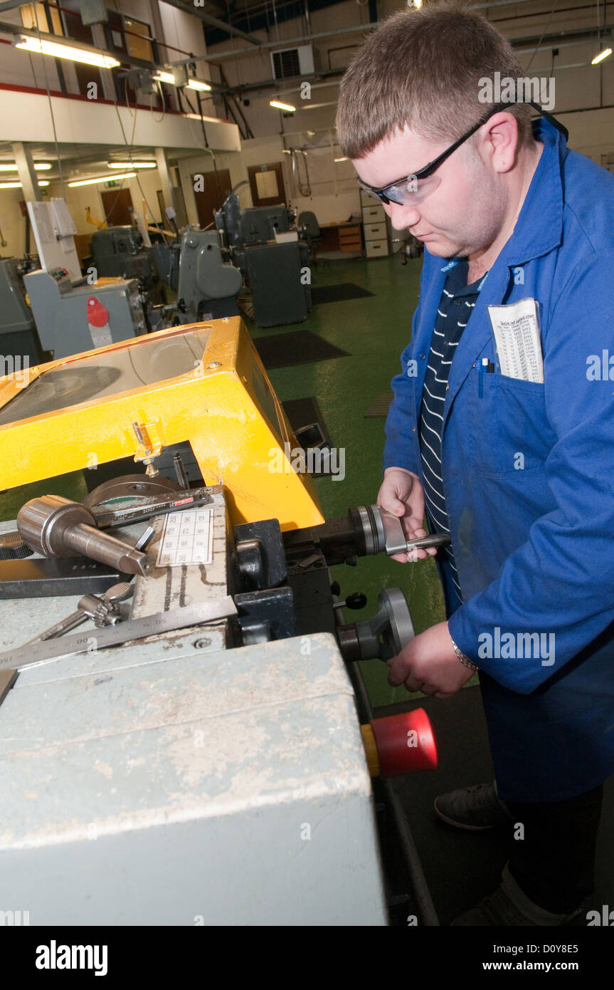 Young white man in blue overalls on a factory floor on an engineering ...