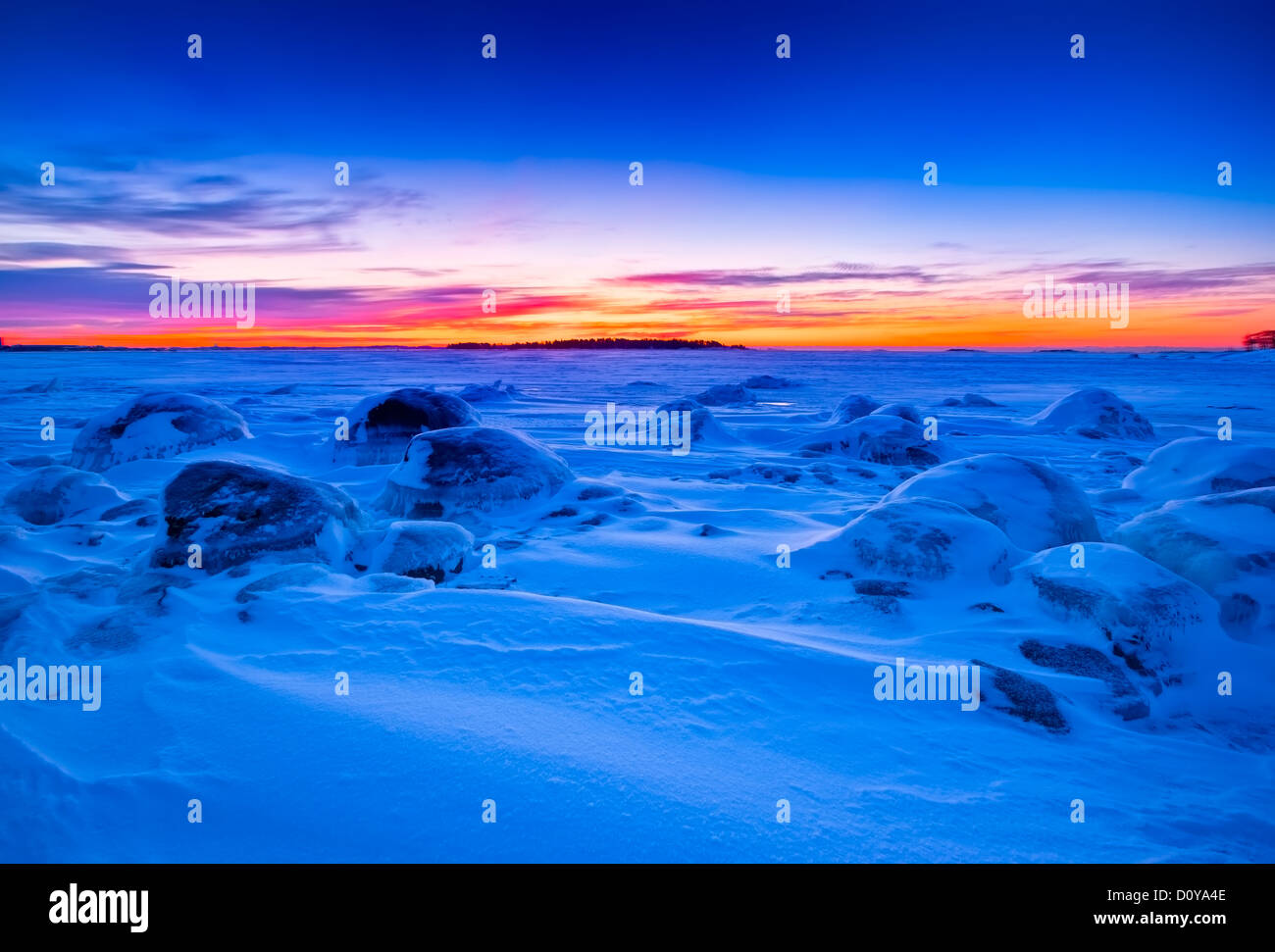 a pink and orange sunrise across a frozen sea and seashore with a blue ...