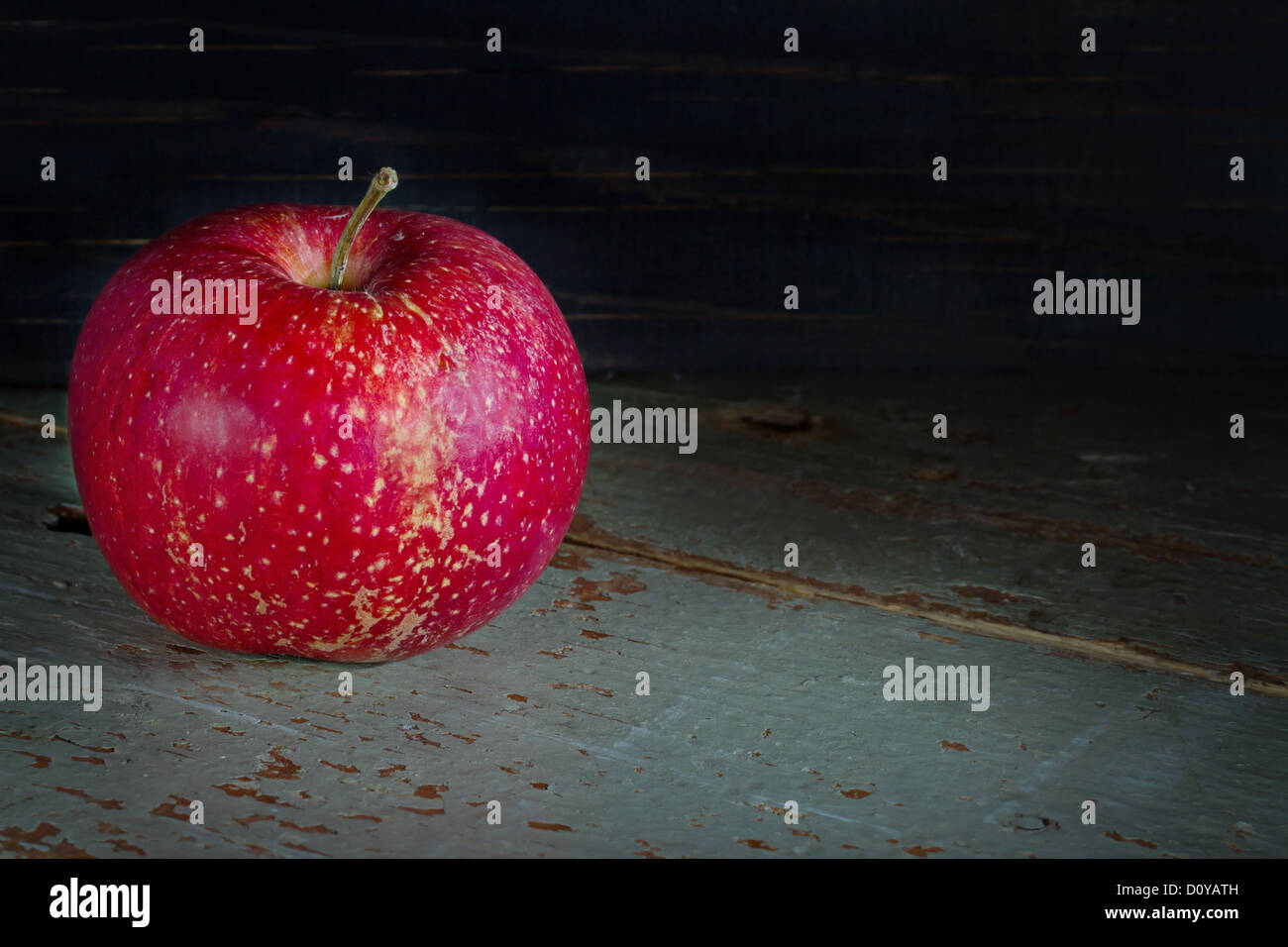 Single red apple on a rustic table with dark background Stock Photo - Alamy