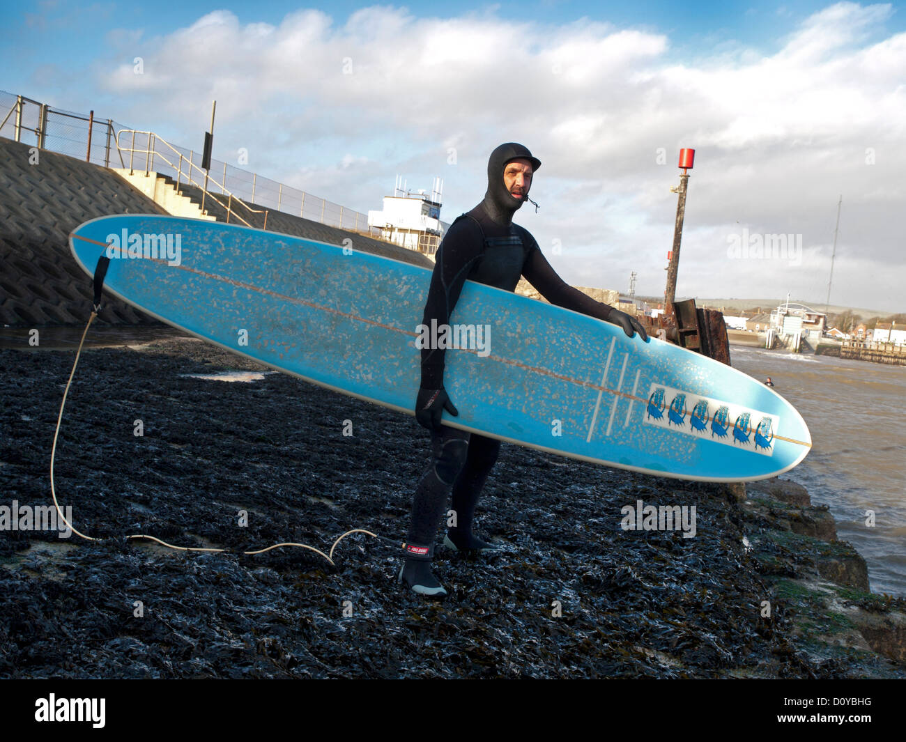 A man prepares to go surfing in Shoreham Harbour, in winter Stock Photo ...
