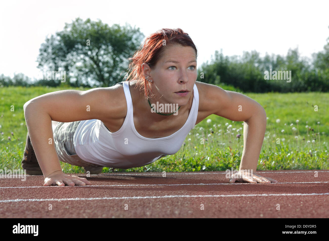 Woman making push-ups warm up training on sports field Stock Photo - Alamy