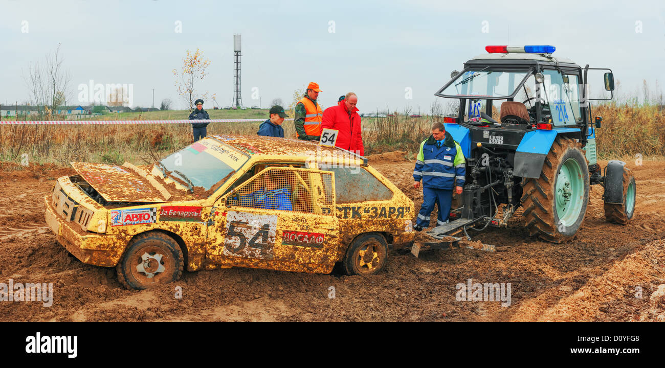 The tractor started to tow the racing car damaged on dirty road Stock ...