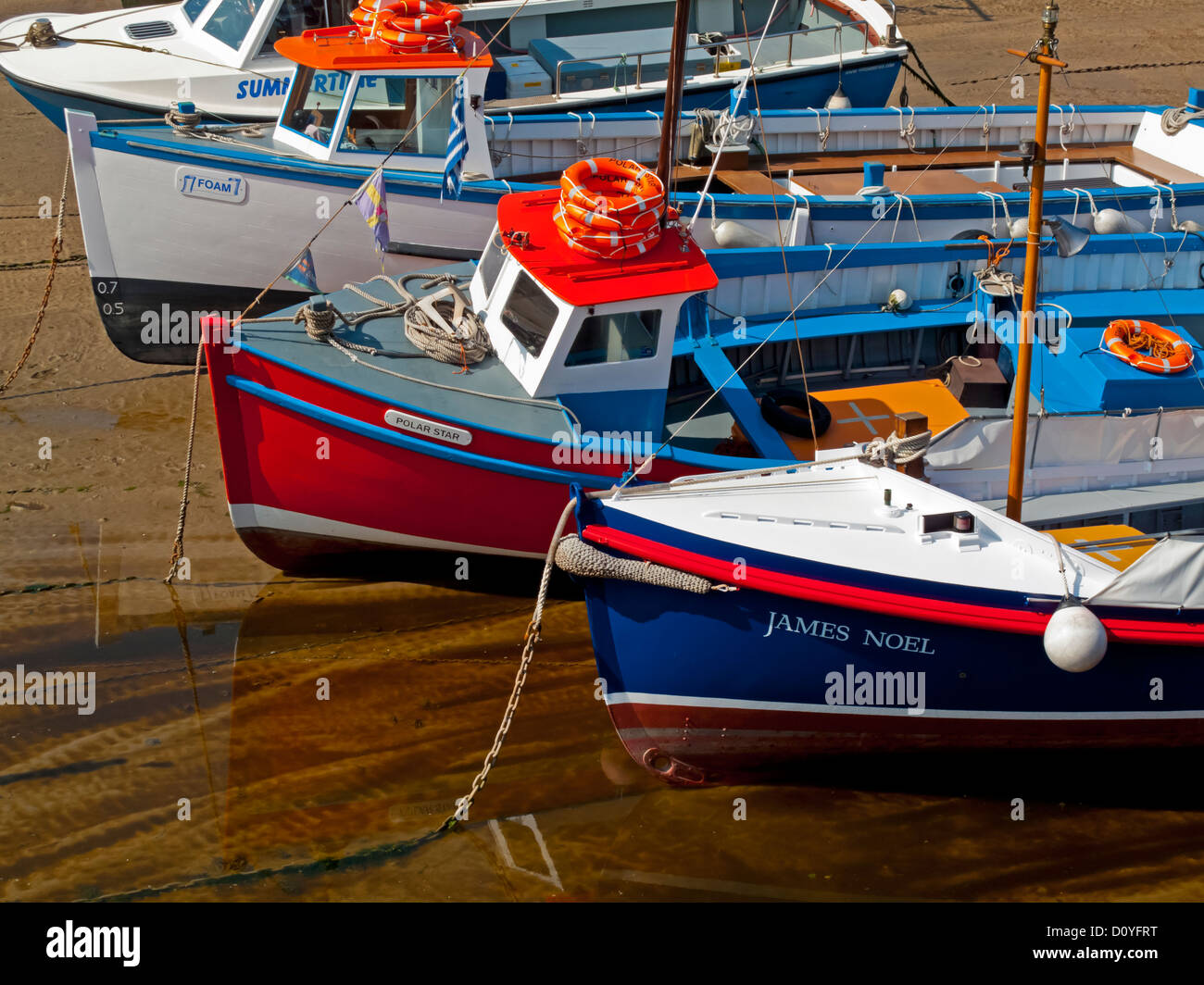 Small boats on the sand at low tide in the Harbour at Tenby ...