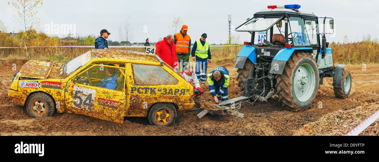 The tractor started to tow the racing car damaged on dirty road Stock ...