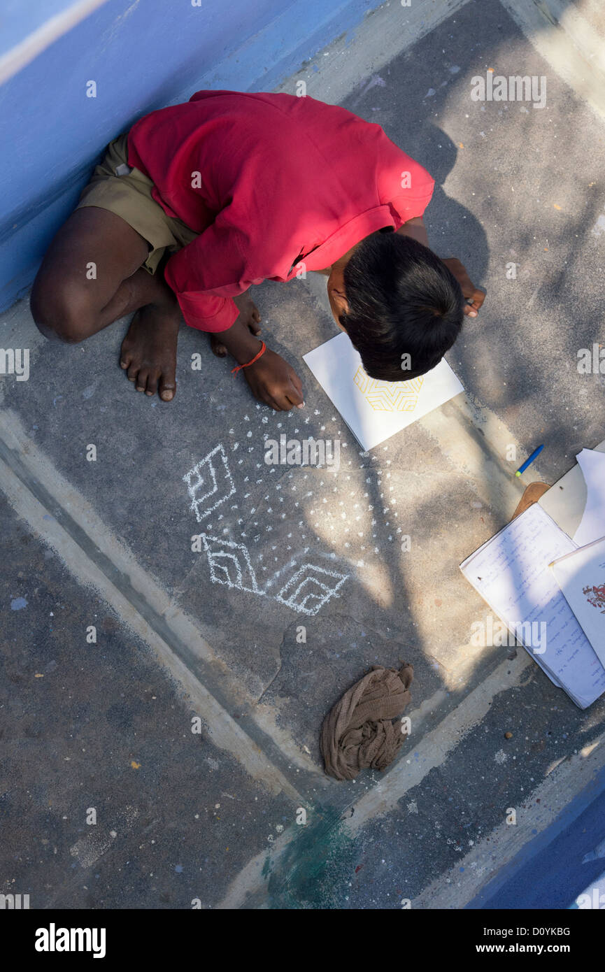 Indian village boy chalking out a rangoli design to be painted outside ...