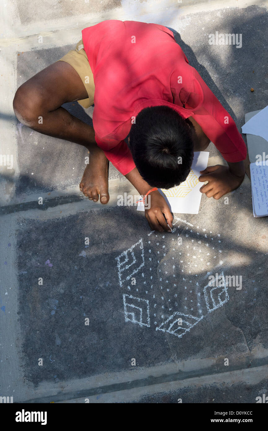 Indian village boy chalking out a rangoli design to be painted outside ...