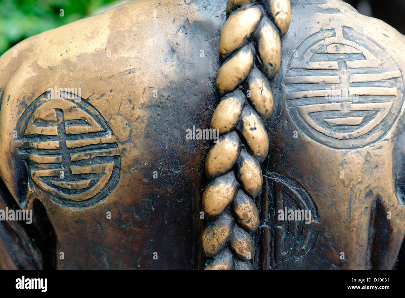 Close up of Chinese symbols and tightly braided hair on the bronze ...