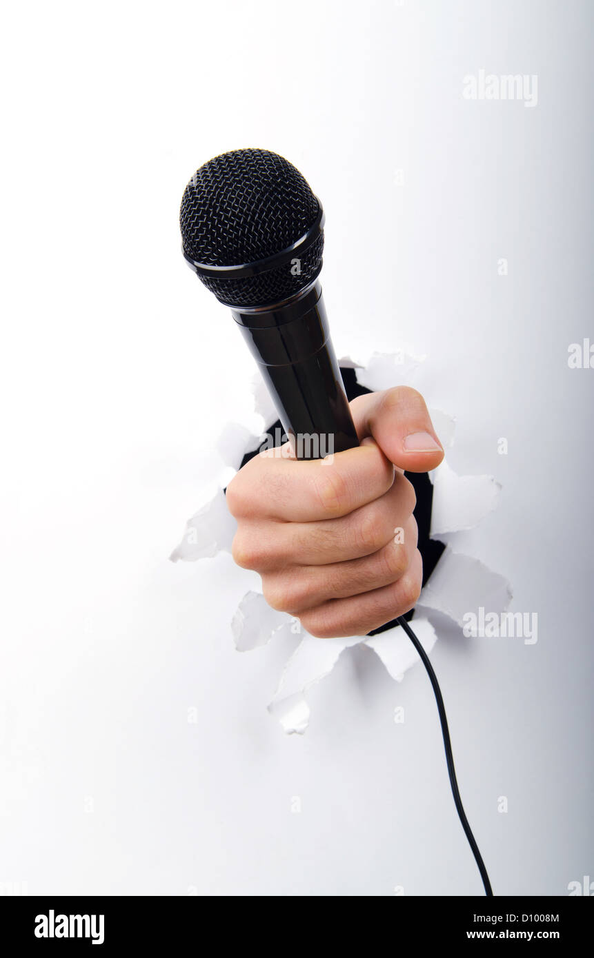 Hand holding microphone through hole in paper Stock Photo - Alamy